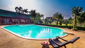 Piscina com espreguiçadeira e mesa com comida.