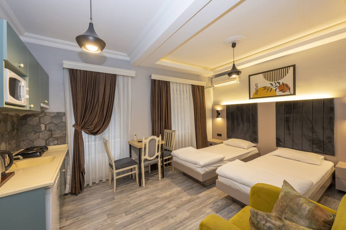 Quarto de hotel com duas camas, uma escrivaninha com cadeira, micro-ondas e área de refeições.