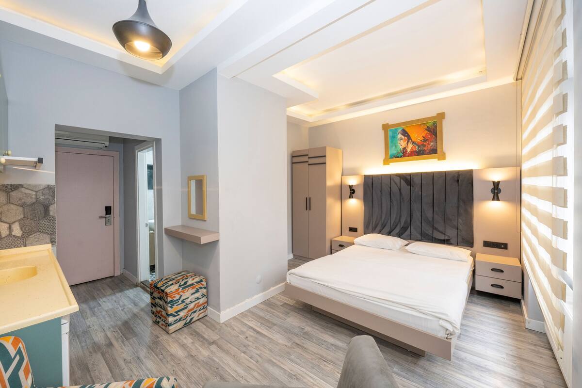 Quarto moderno com cama grande, luminárias de cabeceira, um quadro na parede e um guarda-roupa.