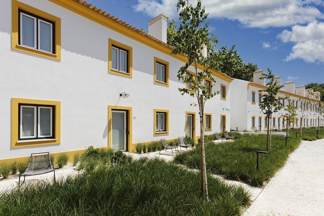 Uma fileira de edifícios brancos com detalhes em amarelo e várias janelas.