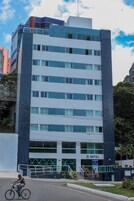 Um edifício de hotel moderno com um letreiro chamativo do 'X Hotel', vários andares e entrada de garagem.