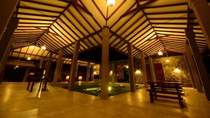 Um espaço interno amplo, com teto alto, vigas de madeira e diversos arranjos de assentos.