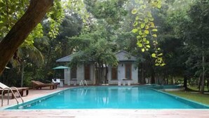 Piscina cercada por árvores e um pequeno edifício com telhado telhado.