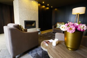 Uma sala de estar moderna com lareira, assentos confortáveis e um vaso decorativo com flores.