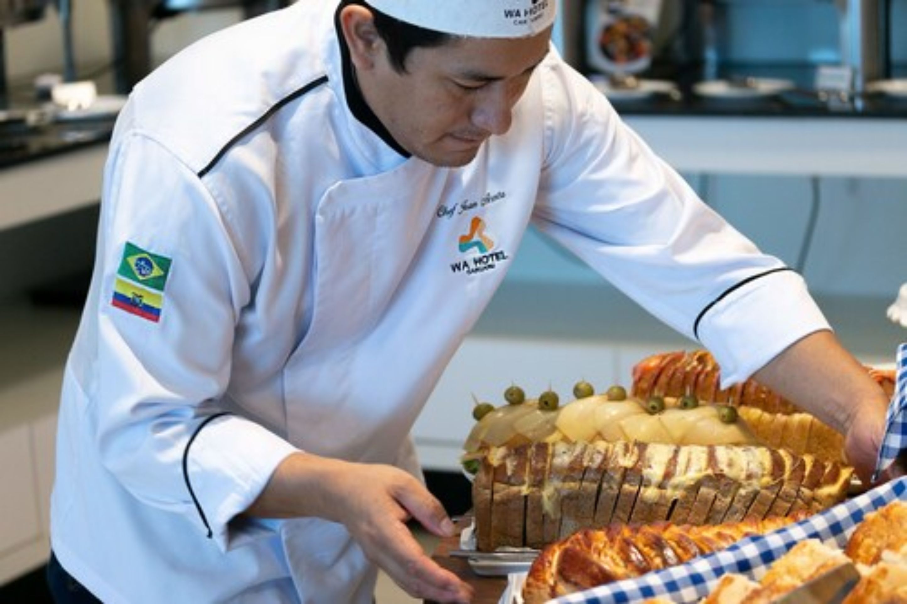 Um chefe de cozinha com uniforme branco e logotipo, preparando comida na cozinha.