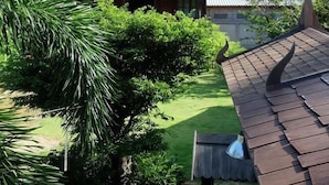 Um edifício de madeira tradicional com telhado inclinado, rodeado por vegetação exuberante e uma montanha imponente ao fundo.
