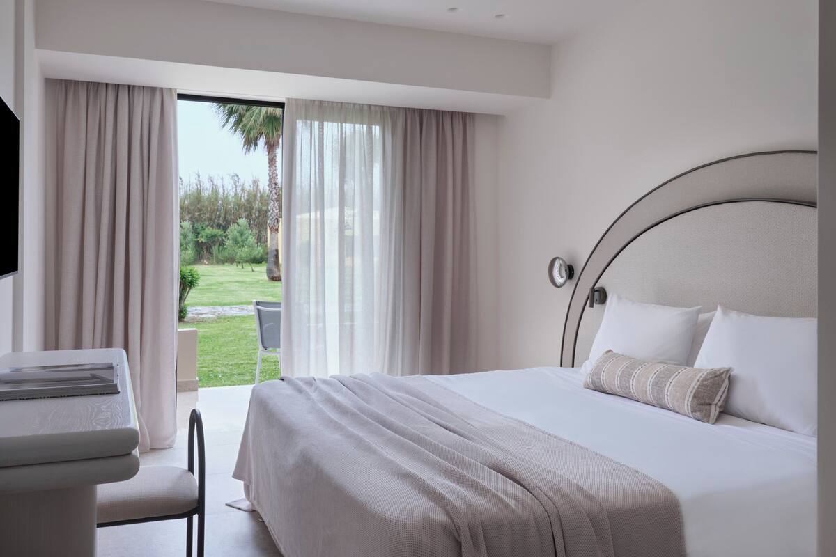 Quarto de hotel com uma cama, uma escrivaninha e vista para o exterior.