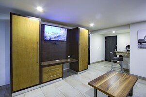 Quarto moderno com uma escrivaninha de madeira, televisão na parede e uma cadeira.
