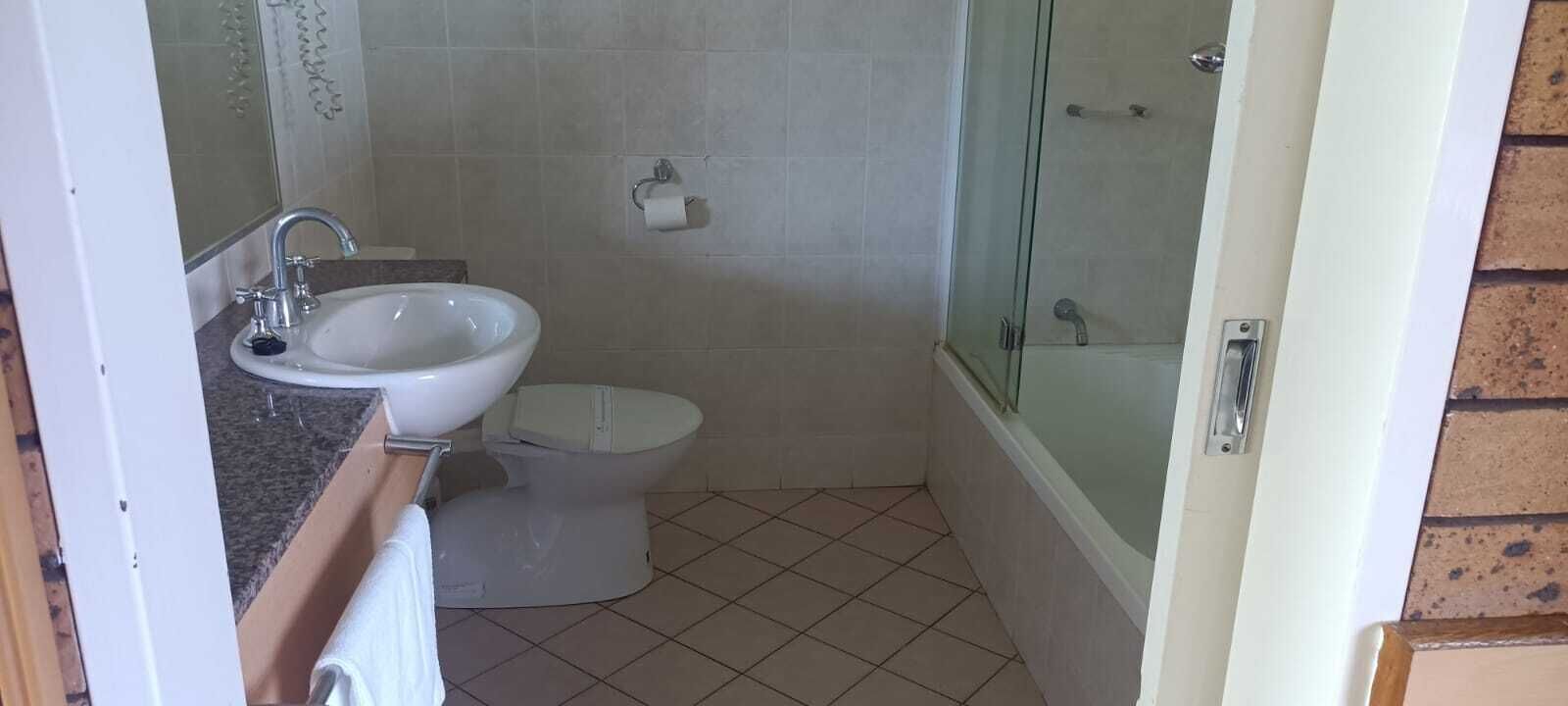 Casa de banho com lavatório, sanita e cabine de duche com vidro.
