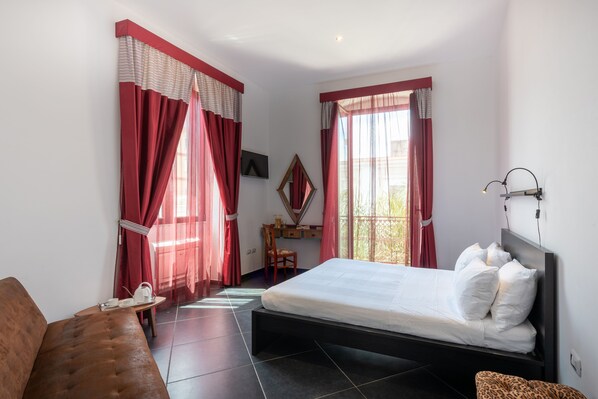Quarto com cama, sofá, escrivaninha e cadeira.