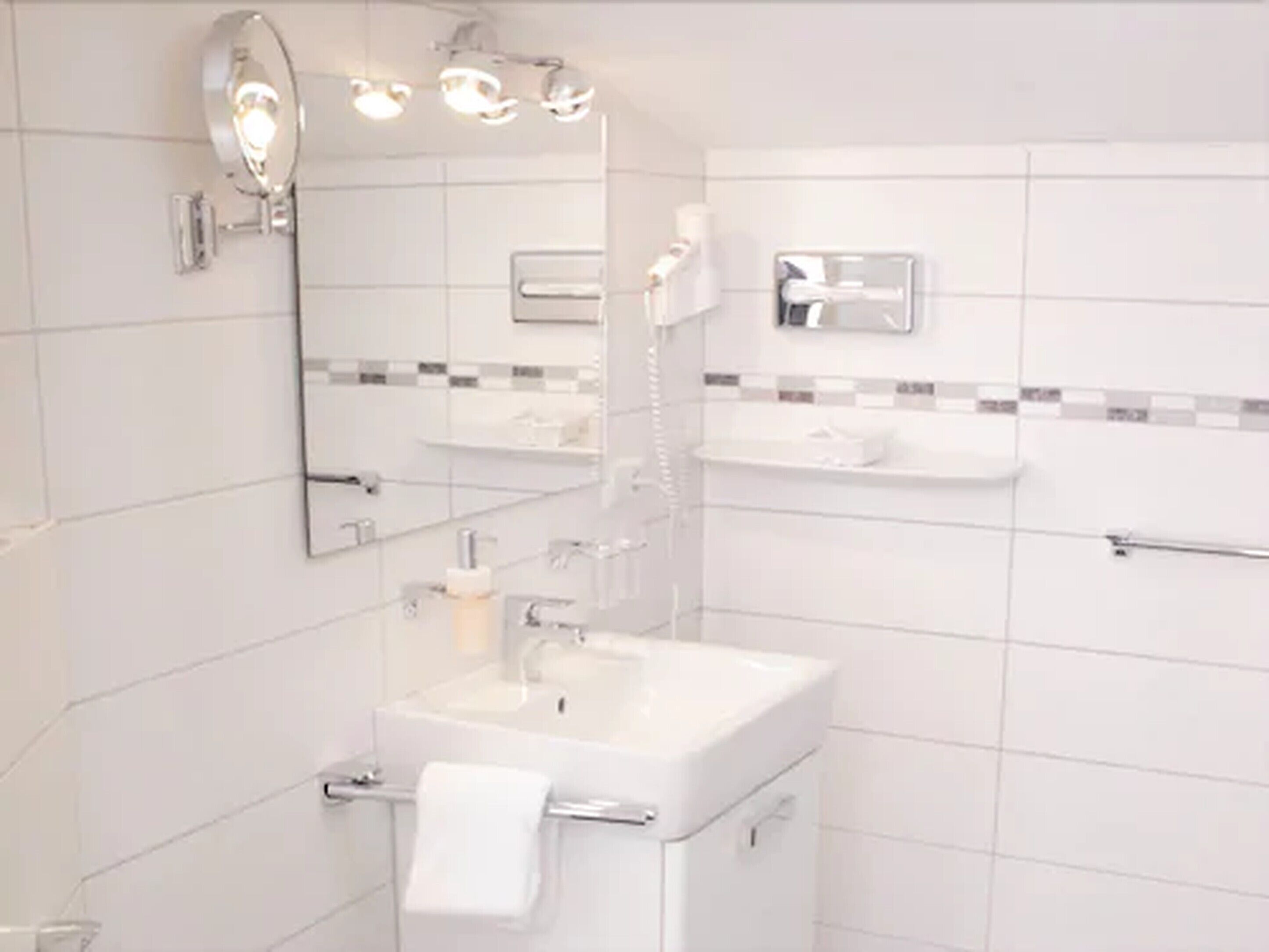 Uma casa de banho moderna com uma pia branca, espelho e porta-toalhas.