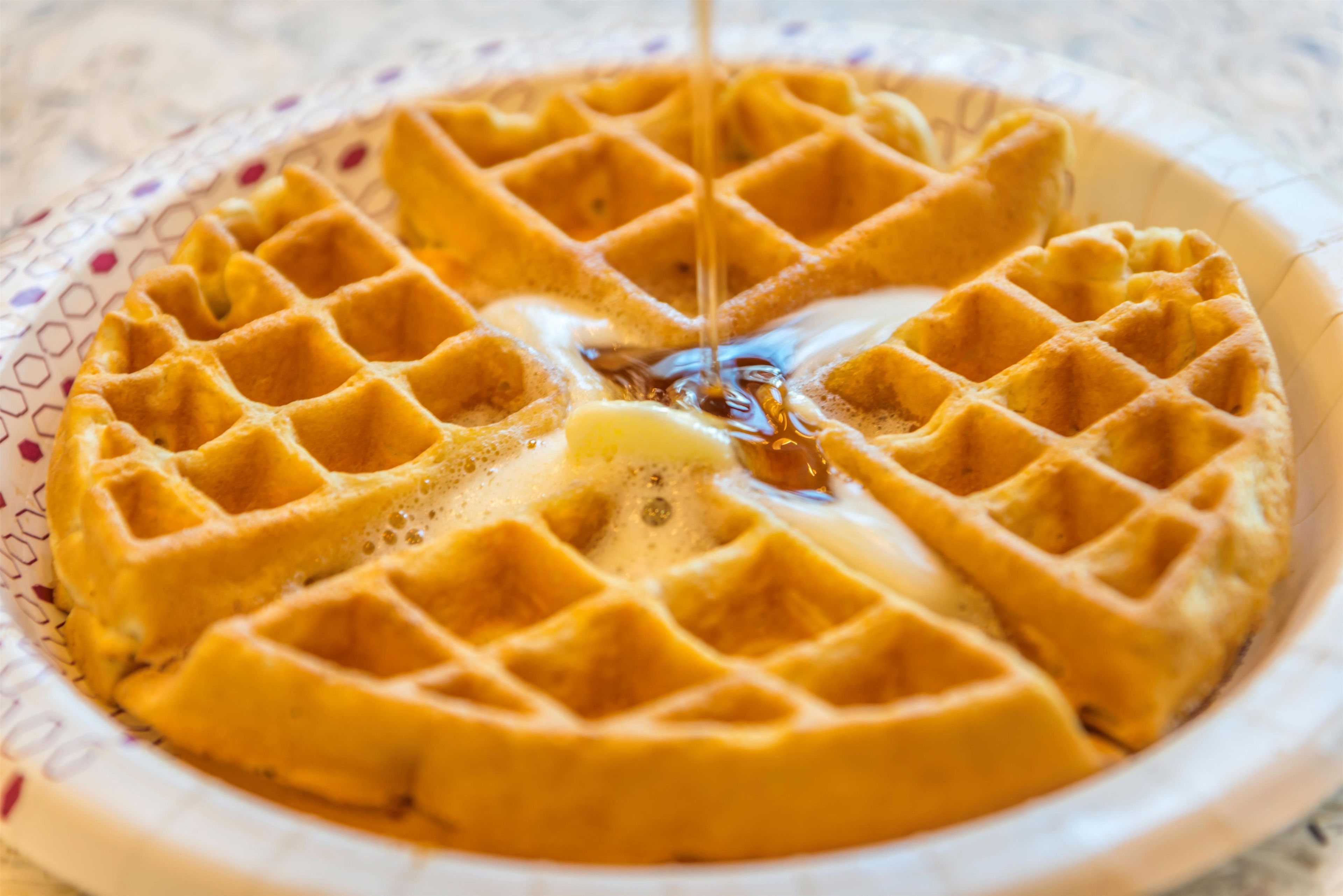 Waffle com xarope sendo despejado.
