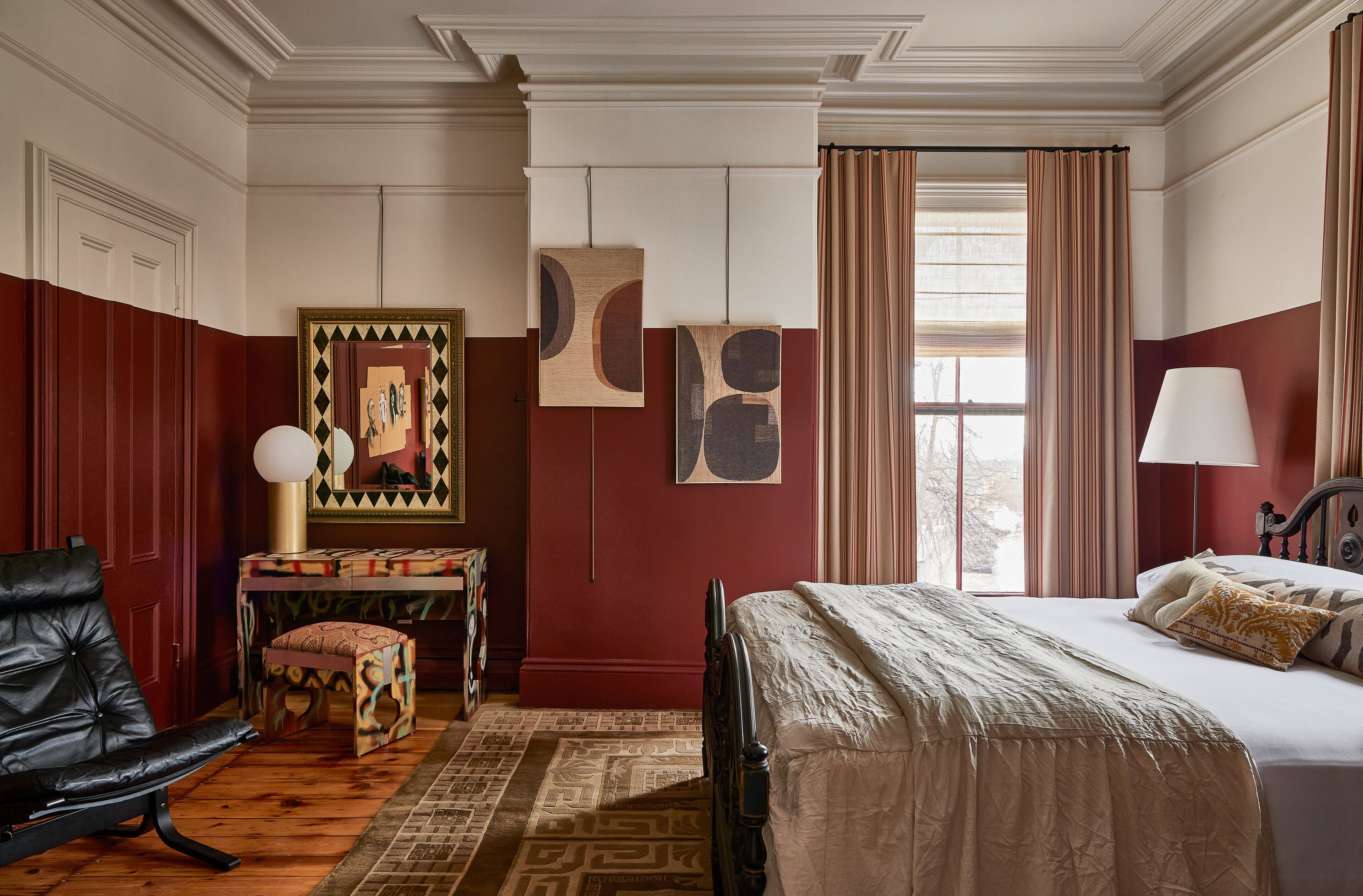 Quarto de hotel com cama, escrivaninha, cadeira e obras de arte nas paredes.