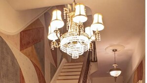 Uma escadaria com corrimão de madeira e um candelabro.