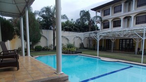 Uma piscina com pergolado e espreguiçadeiras.