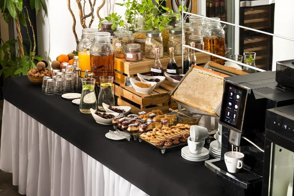 Uma mesa de buffet com diversos alimentos, bebidas e uma máquina de café.