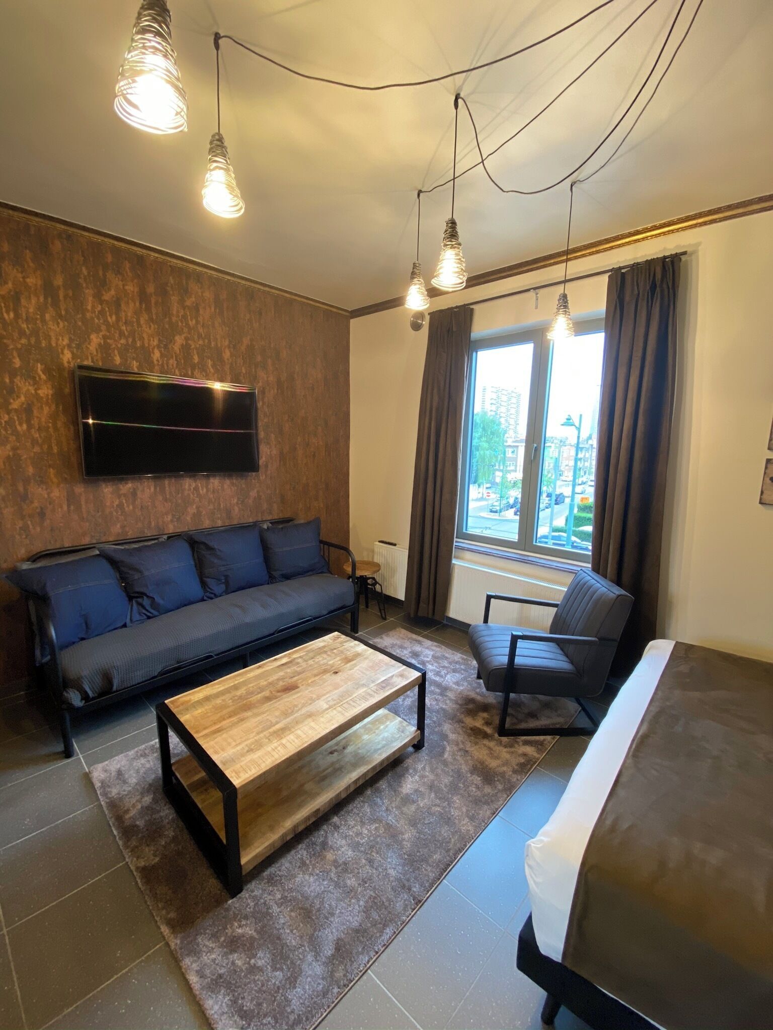 Uma sala de estar moderna com um sofá, uma mesa de centro, uma poltrona e uma TV na parede.