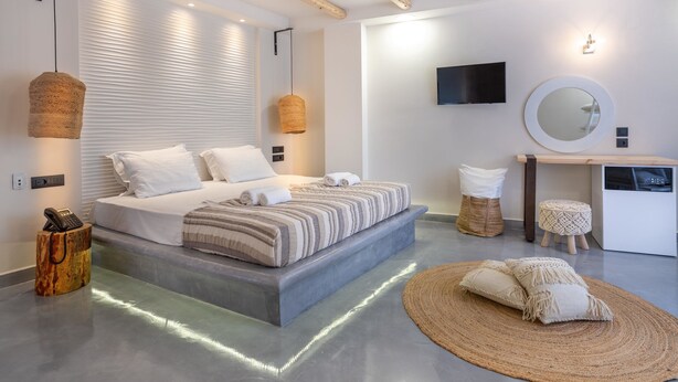 Quarto moderno com uma cama grande, mesas de cabeceira, uma TV e um espelho.