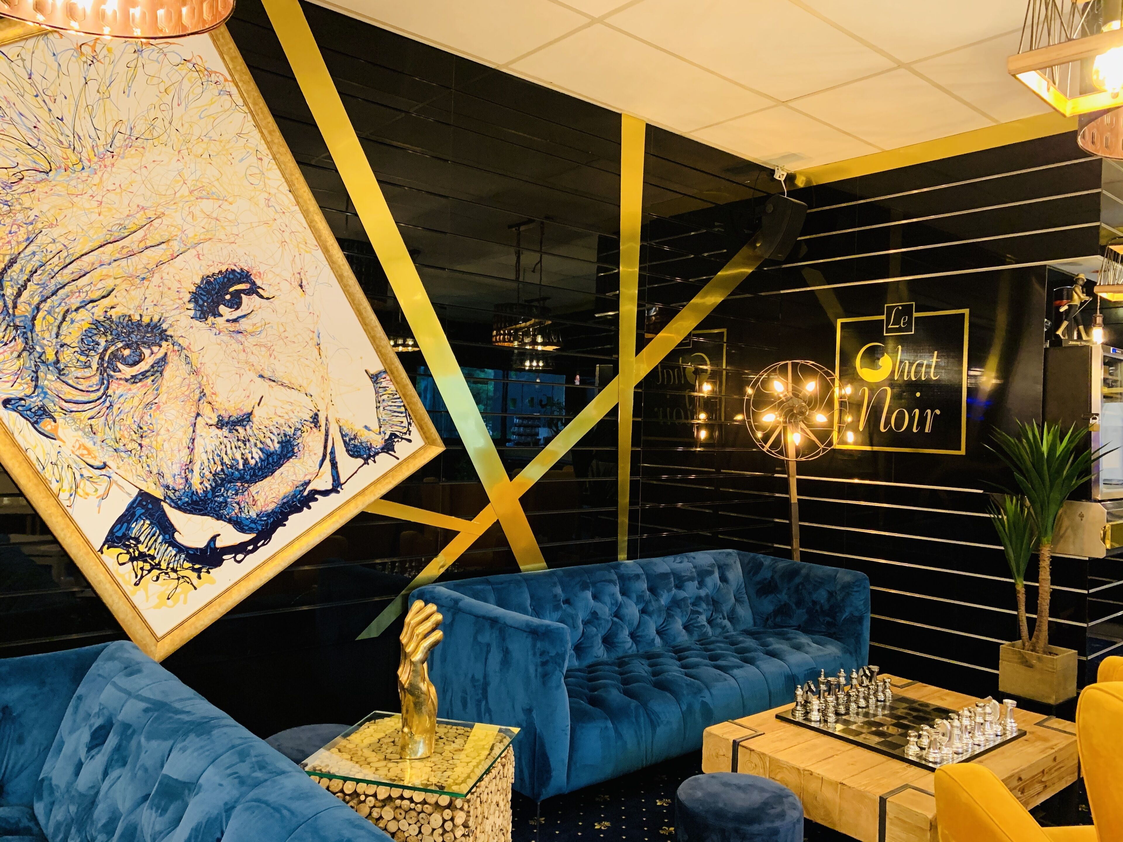 Um interior moderno com um sofá azul, uma mesa de xadrez e uma grande pintura abstrata.