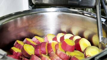 Uma tigela de aço inoxidável cheia de batata doce fatiada.
