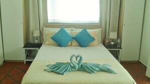 Quarto de hotel com uma cama, duas almofadas, uma mesa de cabeceira, um abajur e uma escultura de toalha em formato de cisne.