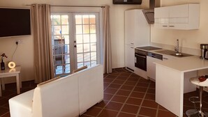 Cozinha compacta com forno embutido, pia e televisão de tela plana fixada na parede.