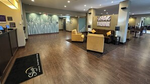 Um saguão de hotel com balcão de recepção, área de estar e painel com um mural floral.