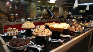 Buffet com diversos alimentos, incluindo bolos, doces e um bolo de chocolate.