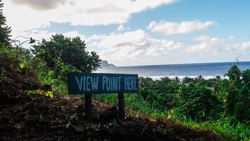 Placa com a inscrição 'VIEW POINT HERE', vista do oceano e céu claro.