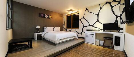 Quarto de hotel moderno com cama, mesa de cabeceira, luminária e escrivaninha com cadeira.