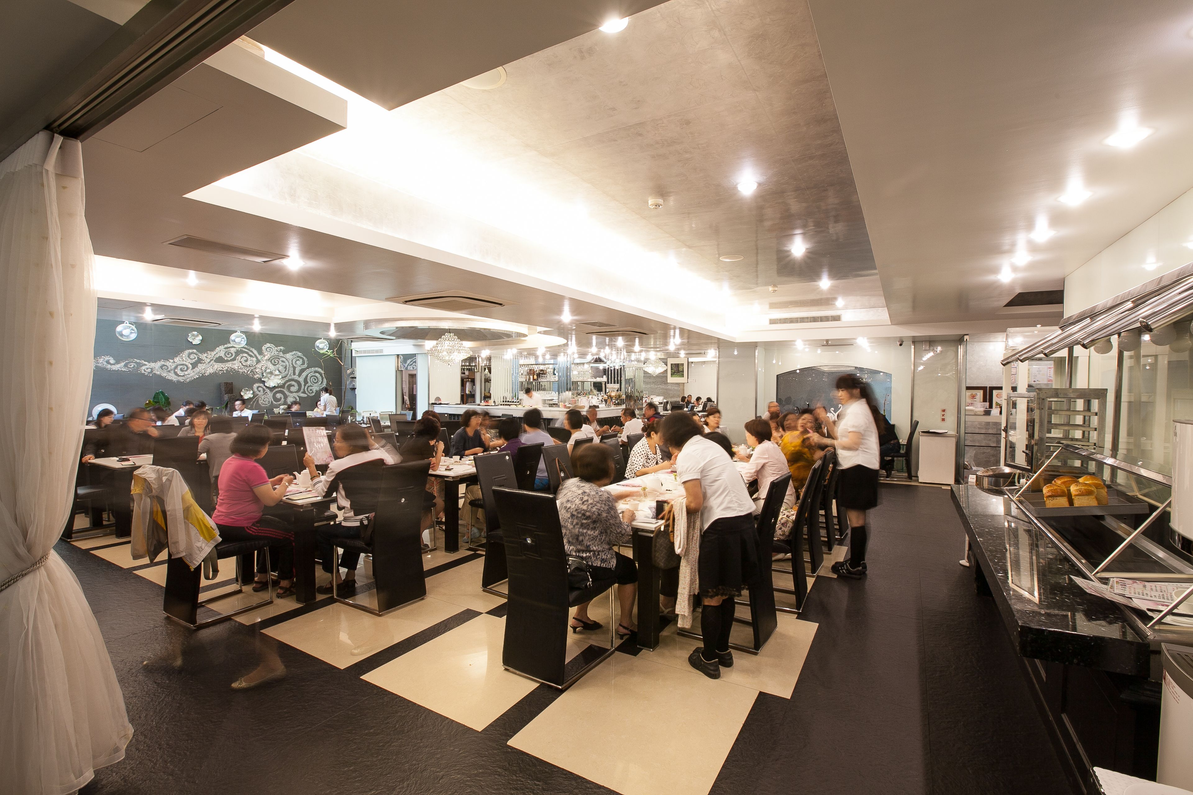 Um restaurante movimentado com várias mesas e cadeiras, uma área de buffet e um design de interiores moderno.