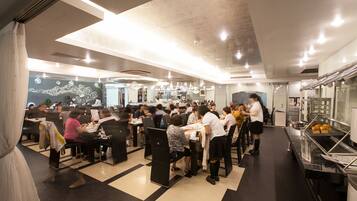 Um restaurante movimentado com várias mesas e cadeiras, uma área de buffet e um design de interiores moderno.