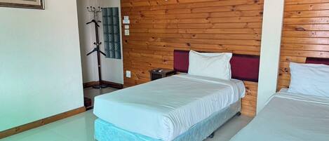 Quarto com duas camas, paredes de painel de madeira, um ventilador de teto e um abajur.