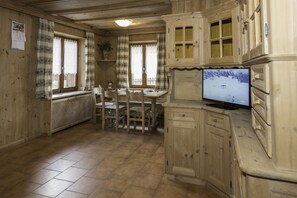 Um interior de madeira com uma área de jantar, uma televisão e armários.