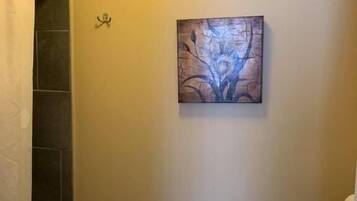 Casa de banho com chuveiro, sanita e um quadro pendurado na parede.