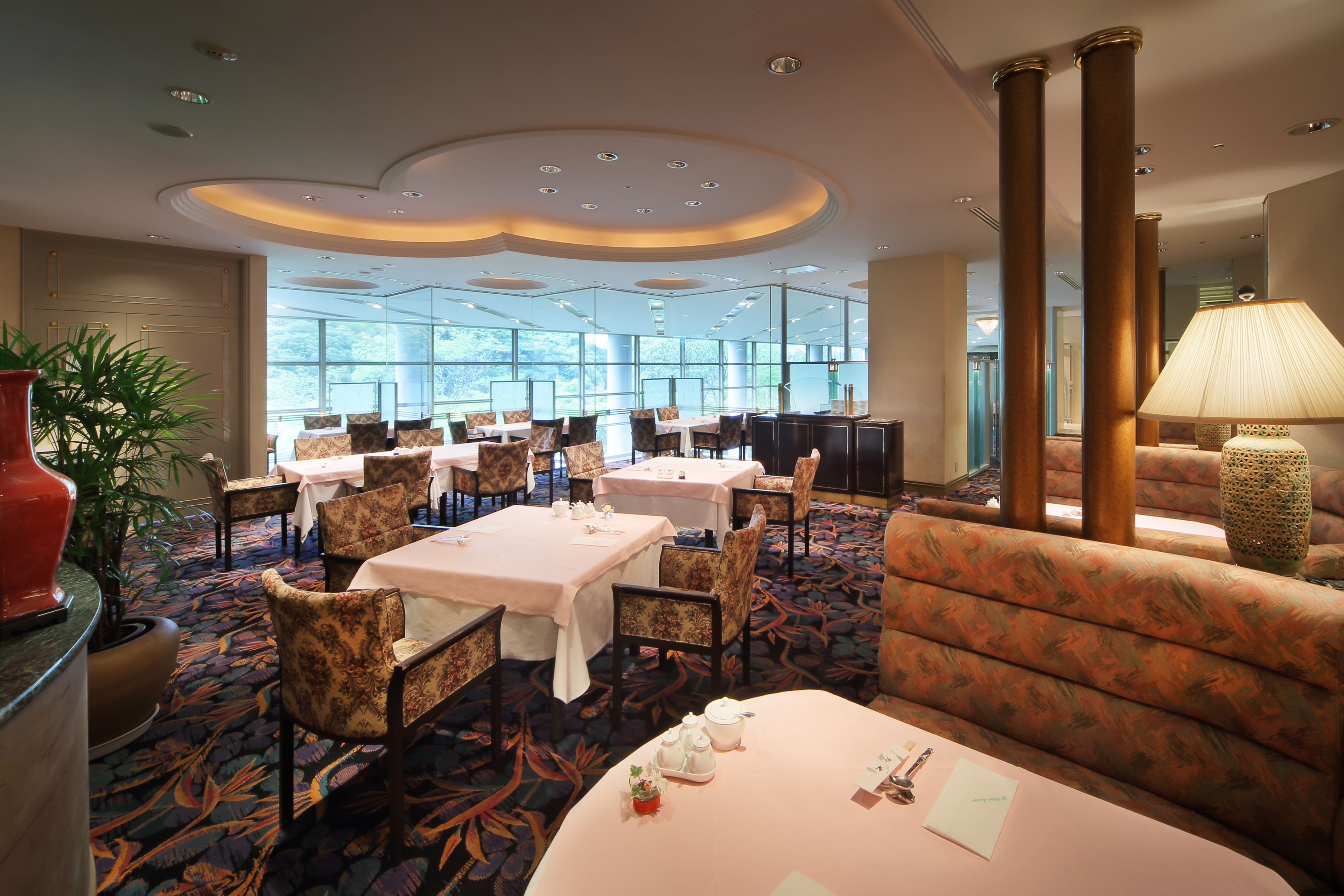Uma sala de jantar de hotel com mesas redondas, cadeiras e um sofá.
