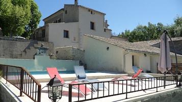 Uma área de piscina com espreguiçadeiras e um muro de pedra.