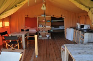 Uma tenda compacta com área de refeições, beliche e cozinha compacta.
