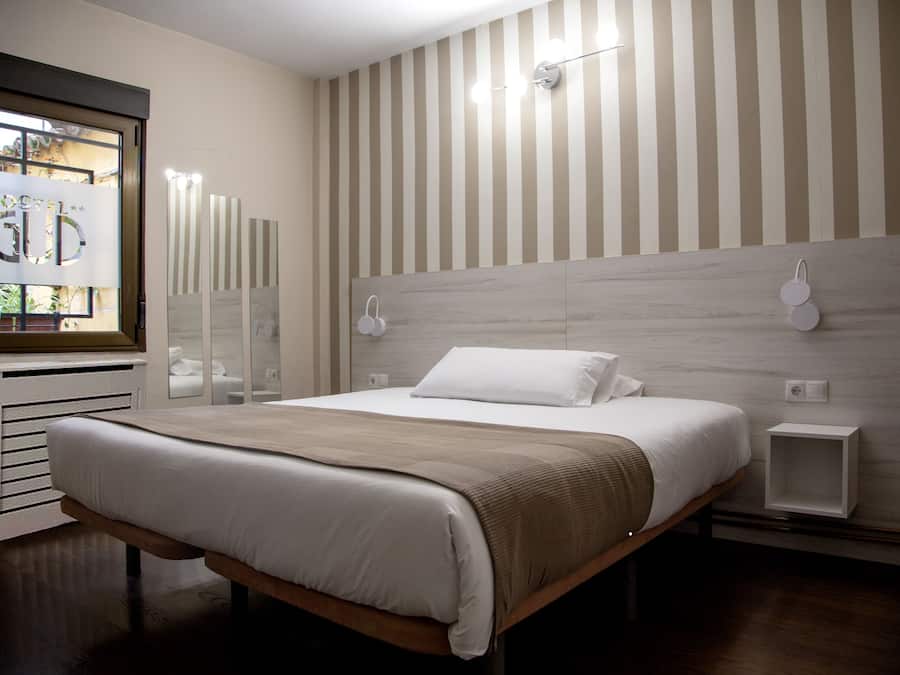 Quarto moderno com uma cama grande, cabeceira de madeira, mesas de cabeceira e janela com vista.