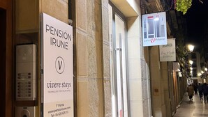 Corredor de hotel com uma placa indicando 'Pension Irune' e 'Lance & Malone'.