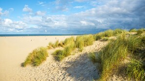 Uma praia com dunas de areia e céu claro.