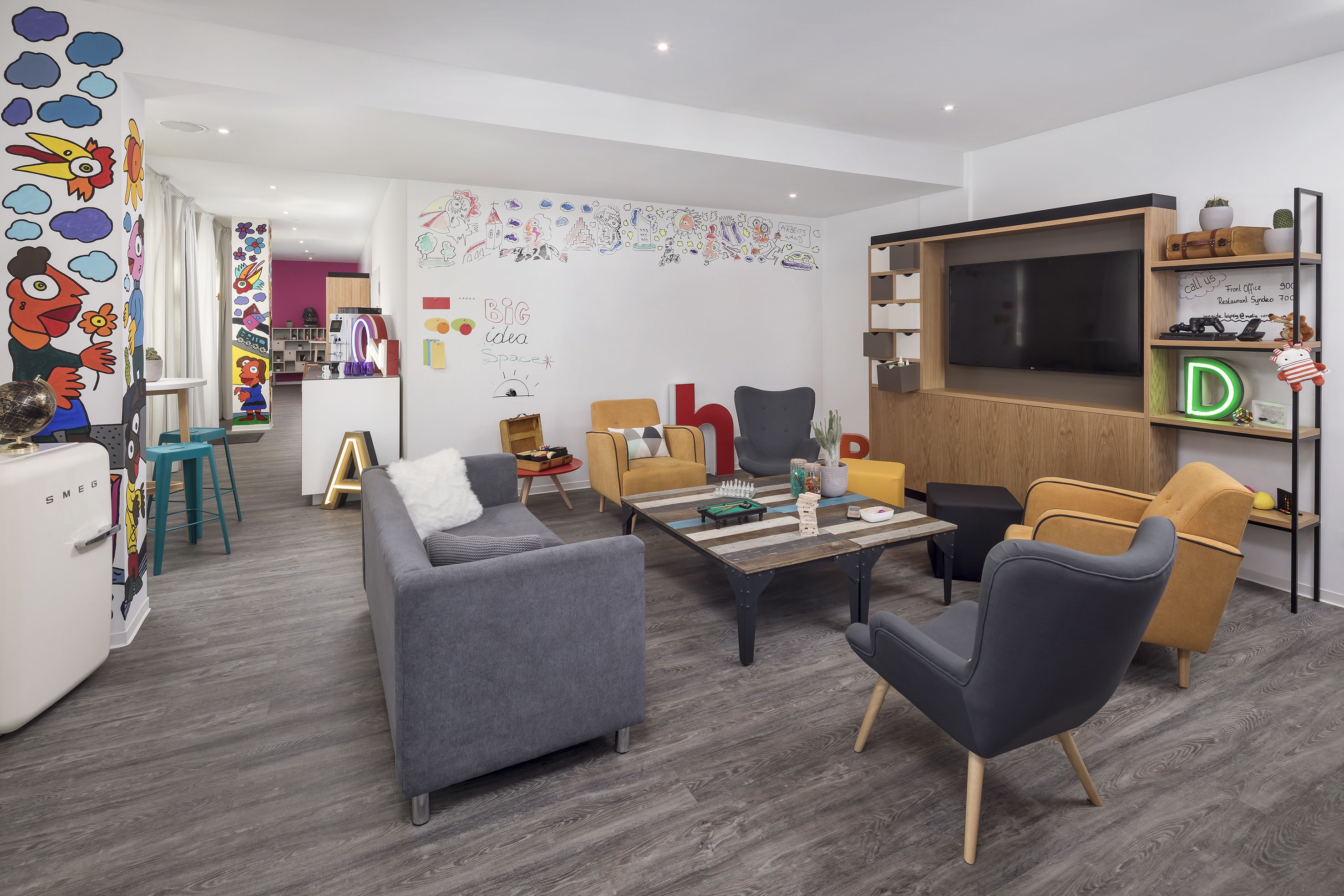 Uma sala de estar moderna com um sofá cinzento, uma mesa de centro e um rack para TV. Há uma estante com um letreiro neon 'D' e um letreiro 'Ligue para Nós'.
