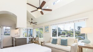Quarto de hotel com cama, sofá, mesa de jantar e ventoinha no teto.