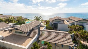 Uma área residencial costeira com várias casas, uma piscina e vista para o oceano.