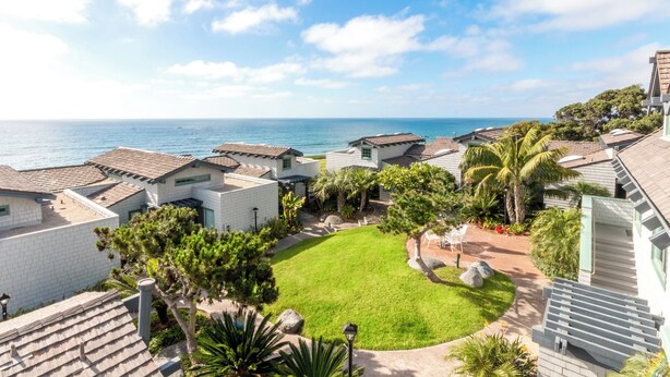 Uma área residencial costeira com casas, um gramado bem cuidado e vista para o oceano.