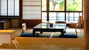 Quarto japonês tradicional, com chão de tatame, uma mesa baixa e portas deslizantes.