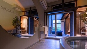 Interior moderno de hotel com uma ampla piscina interna, banheiro visível com banheira e uma área de recepção com planta.