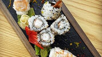 Uma bandeja de sushi com diversos rolinhos e camarões em um prato de ardósia preta.