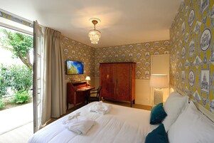 Quarto de hotel com cama, escrivaninha, televisão e guarda-roupa.