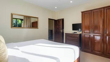 Quarto com cama grande, guarda-roupa, televisão e espelho.
